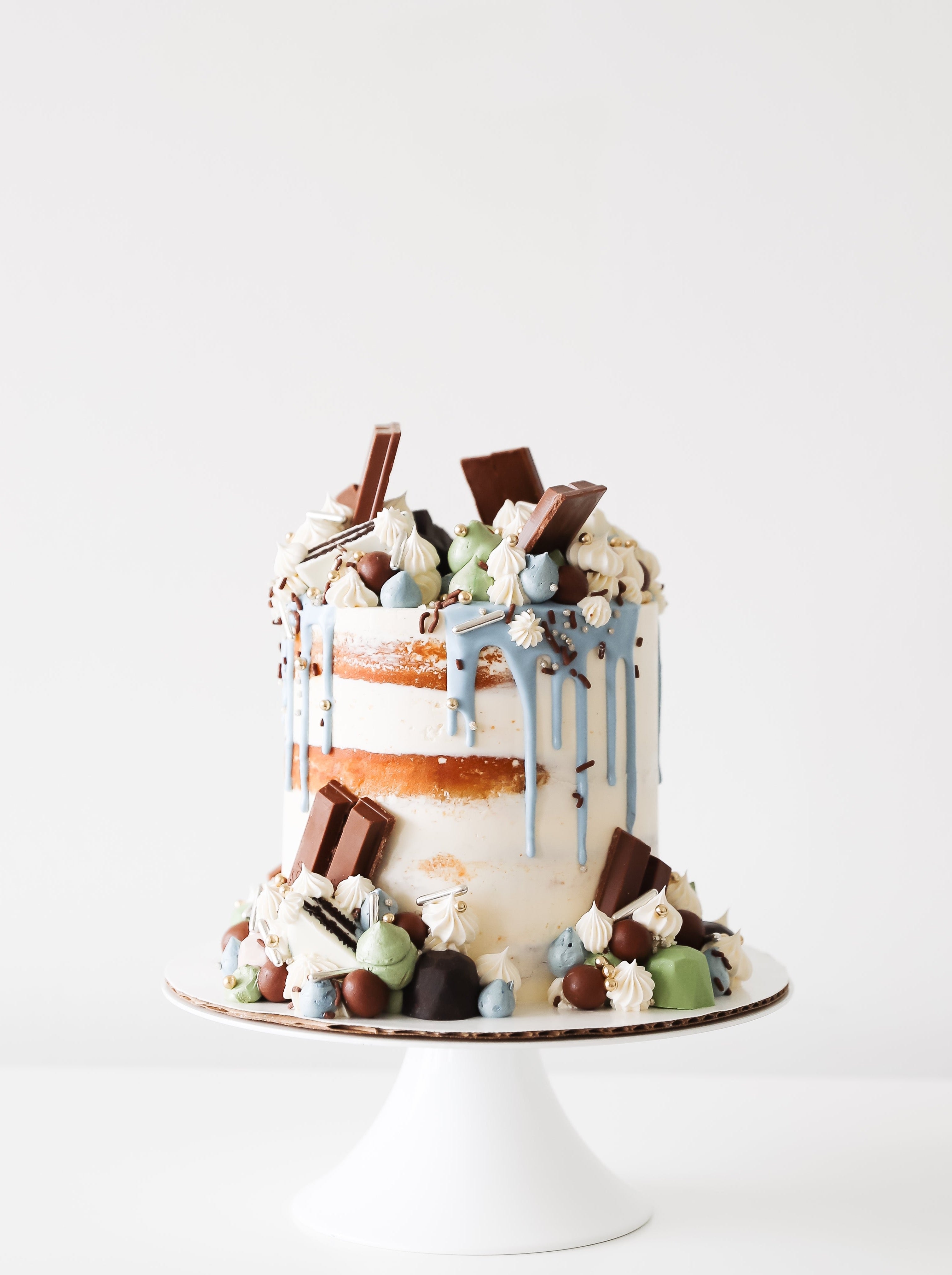 Semi-Naked Drip Cake with Chocolate Candy and Blue Drips – Earth and Sugar